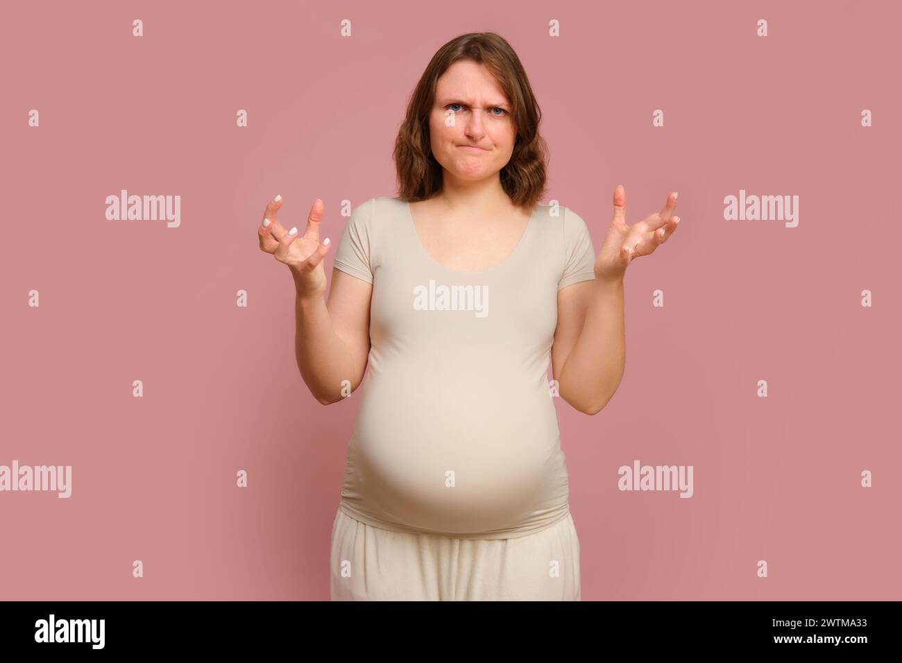 Angry pregnant woman on studio pink background. Pregnancy of an evil ...