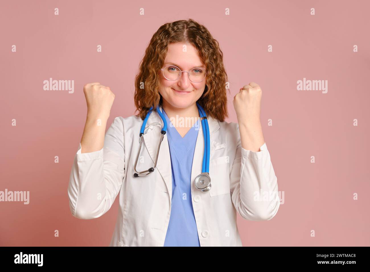 Woman doctor in a victorious gesture, studio pink background. Nurse in ...