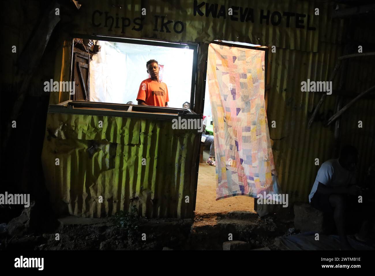 A man gazes through a restaurant window in Kibera Slum. Kibera, the ...