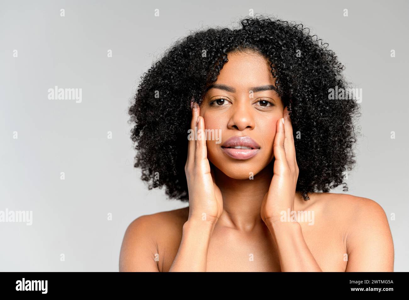 Contemplative African-American woman holds her face in her hands, her ...