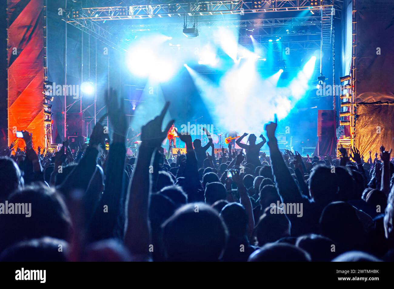 Crowd enjoying a night-time rock concert under vibrant stage lights ...