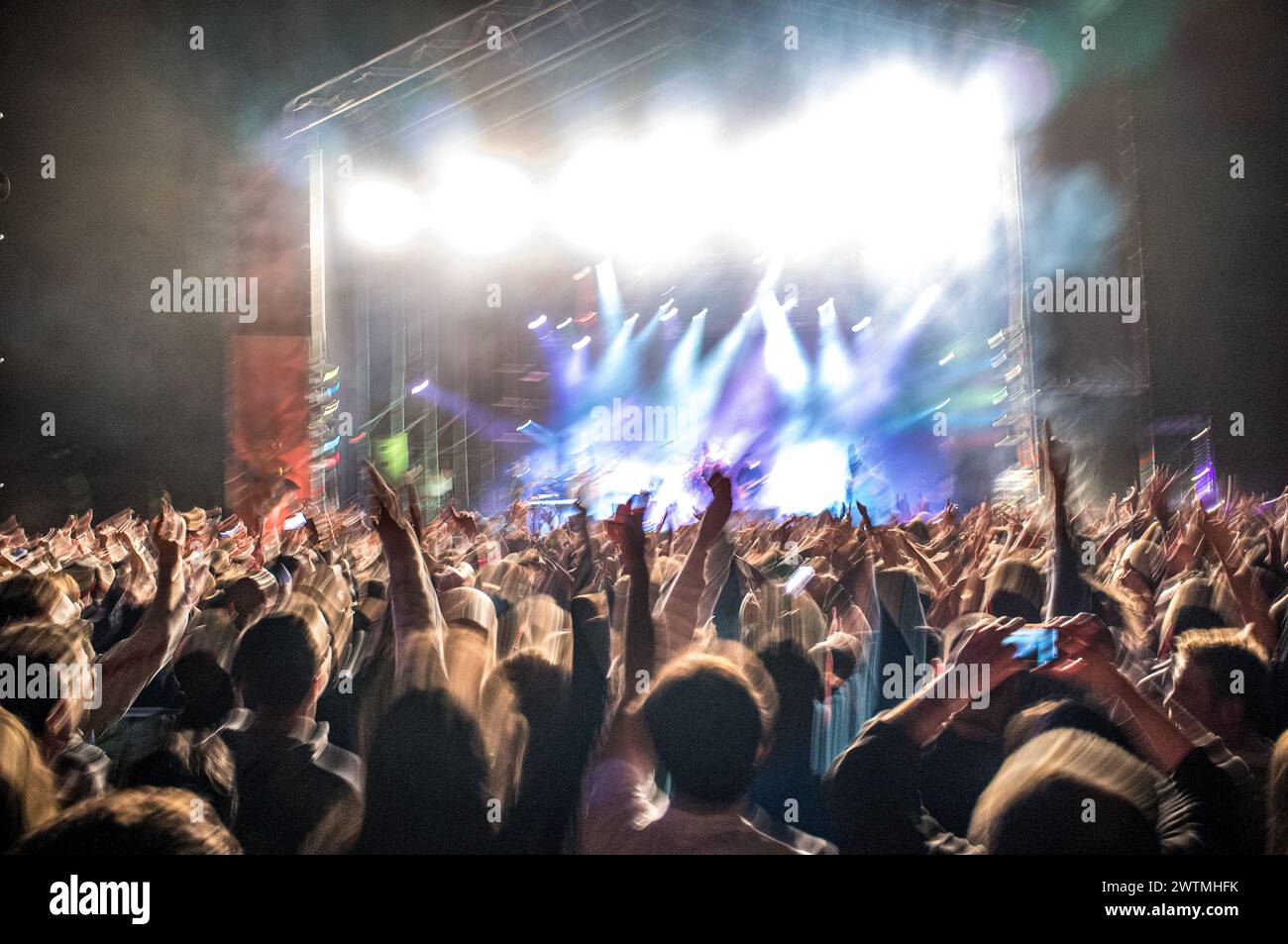 Crowd enjoying a night-time rock concert under vibrant stage lights ...