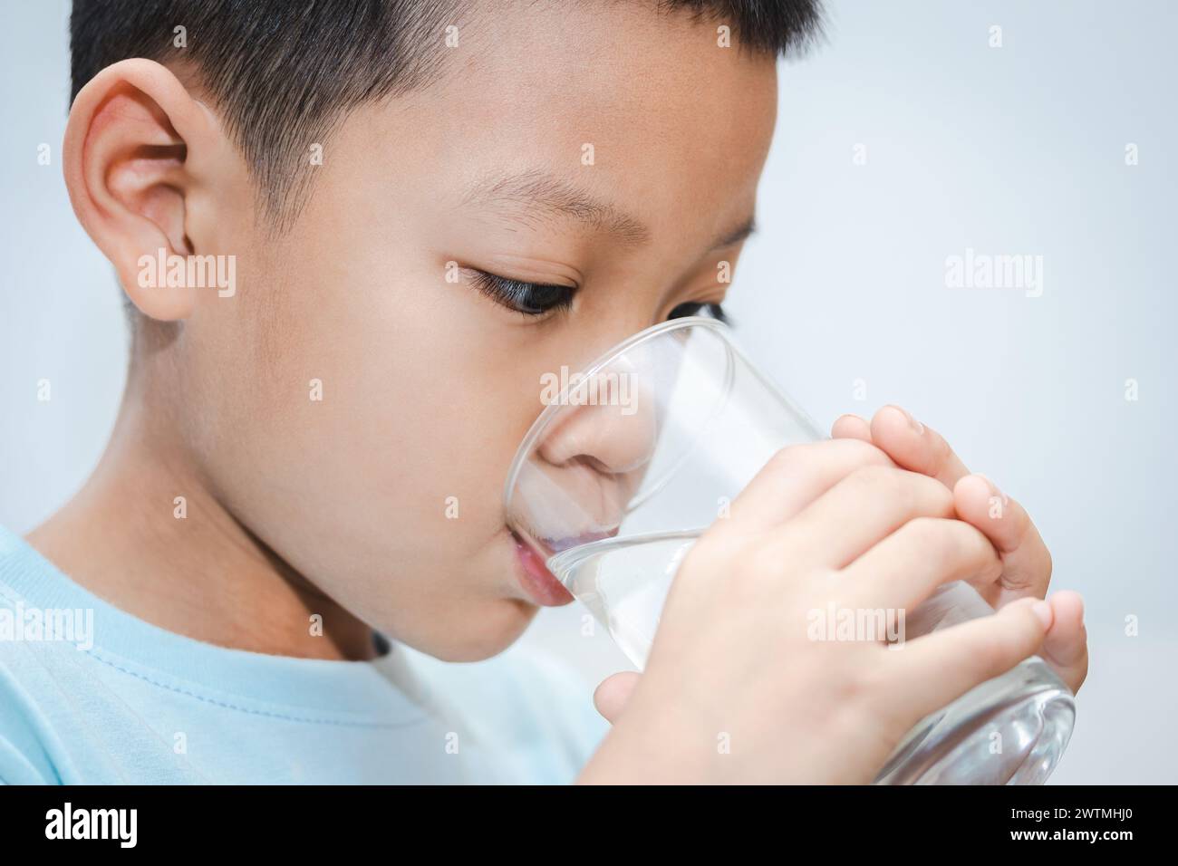 little Asian boy drinks water from a glass. shot of a child drinking a ...