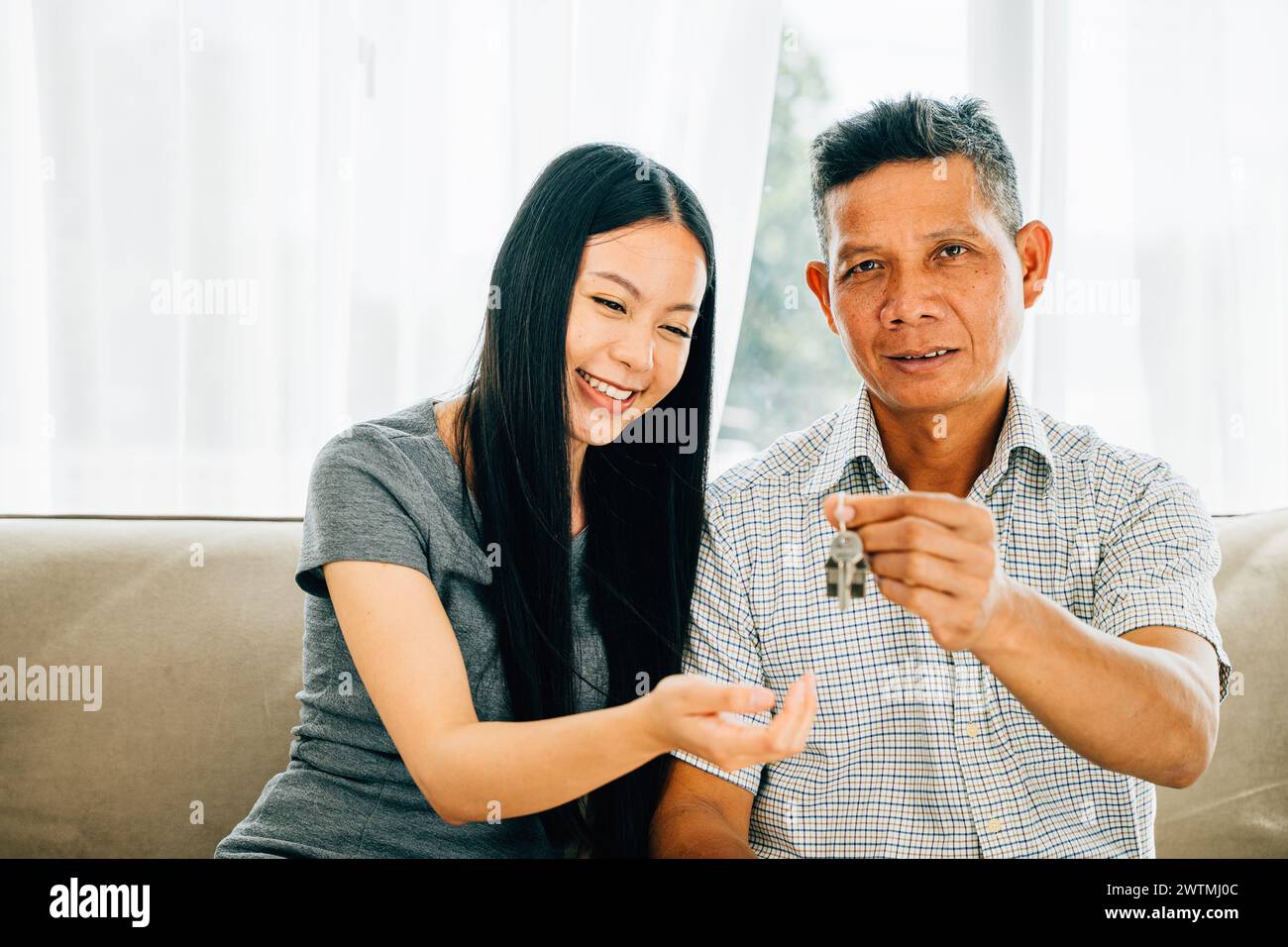 A delighted couple celebrates new homeownership displaying keys to ...