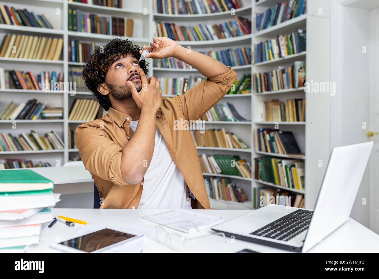 Concentrated islamic man with curly hair throwing head back while using ...