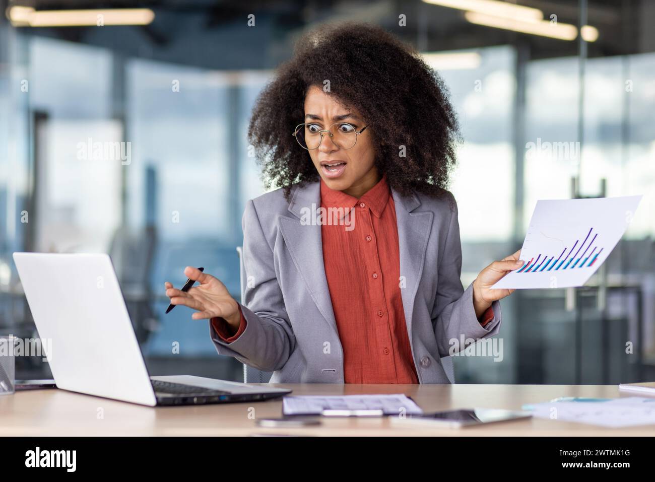 Confused head of department holding sheet with charts and pen in raised ...