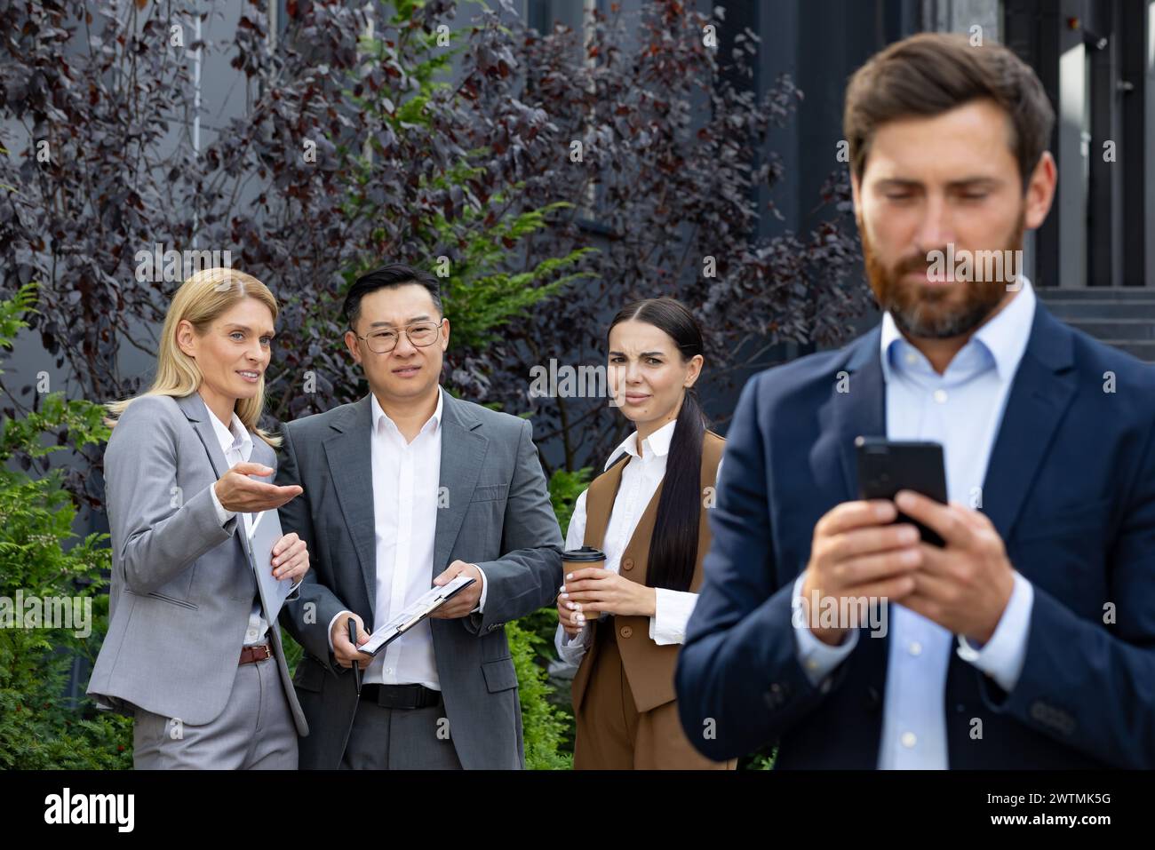 Diverse group of colleagues standing behind man with cell phone in ...