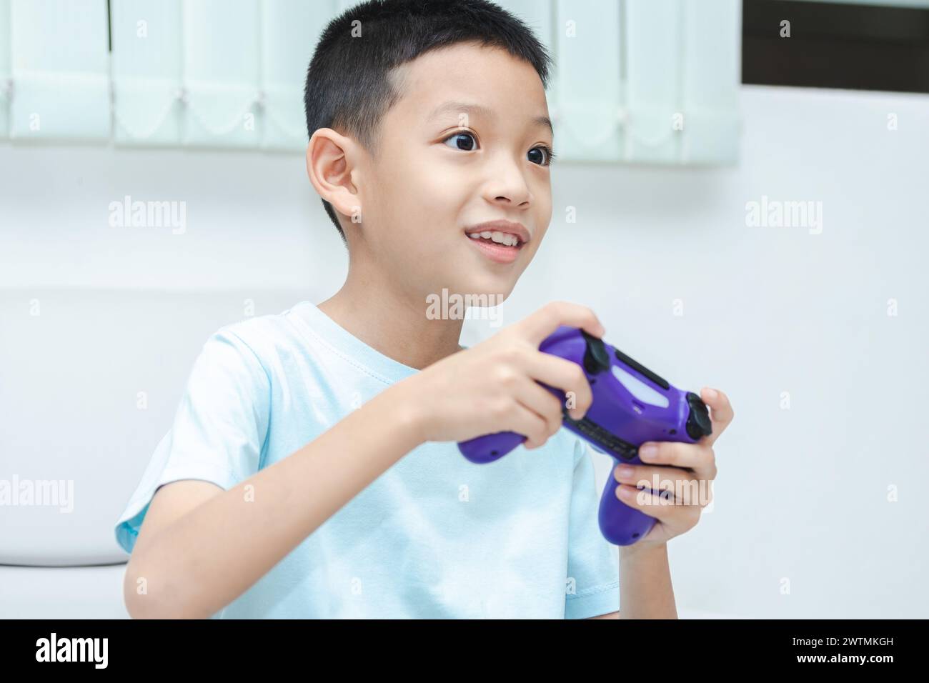 little Asian boy playing a video game. shot of a child holding a game ...