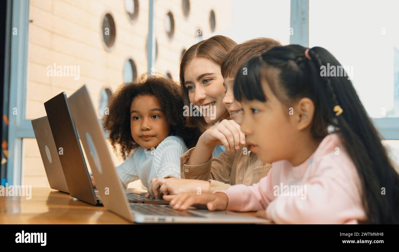 Smart teacher teaching and looking student using laptop at classroom ...