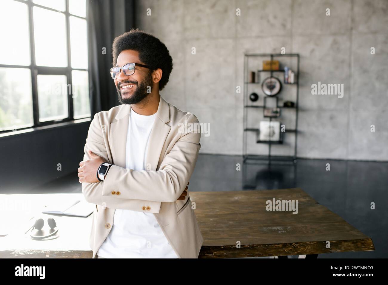 Young businessman in a beige suit strikes a pose with his arms ...