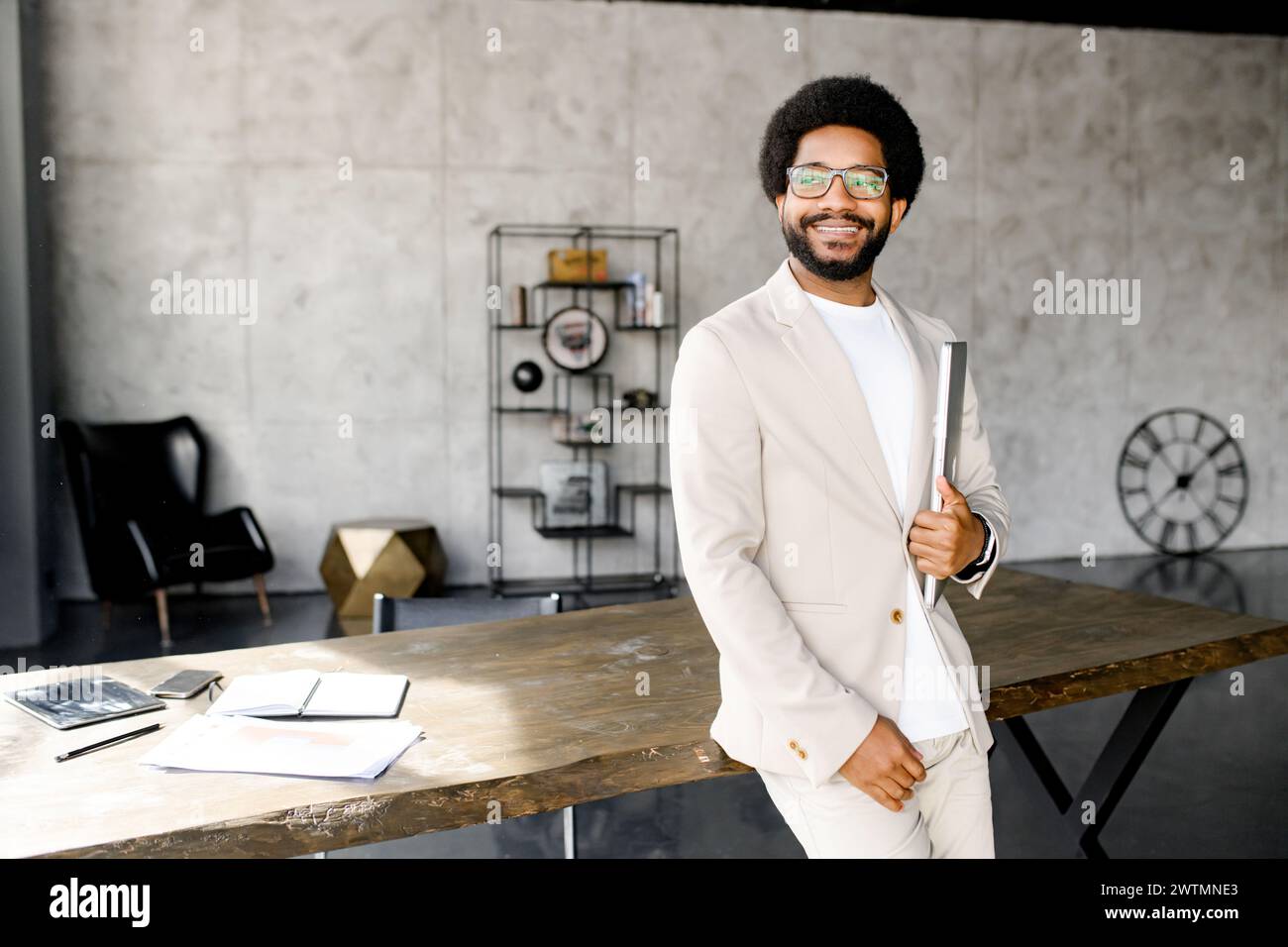 A modern Brazilian businessman stands poised with his laptop, his smart ...