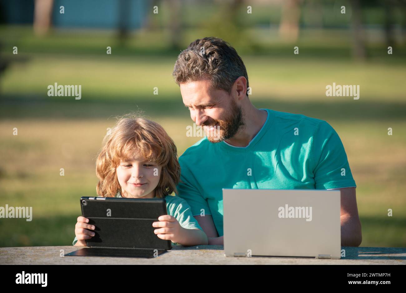 Happy father using laptop relax with schooler son holding laptop have ...