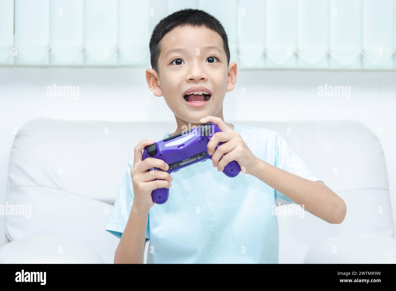 little Asian boy playing a video game. shot of a child holding a game ...