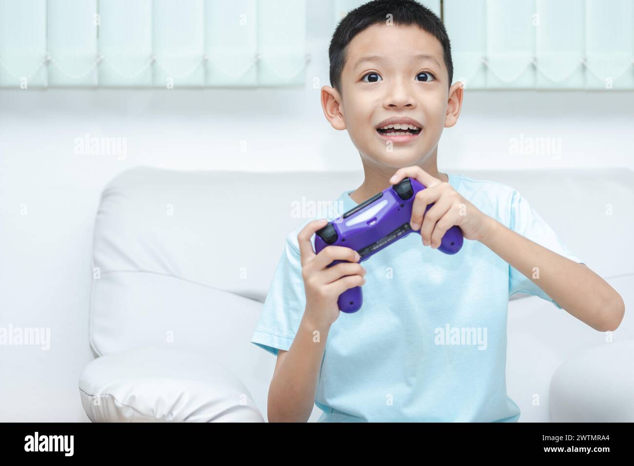 little Asian boy playing a video game. shot of a child holding a game ...
