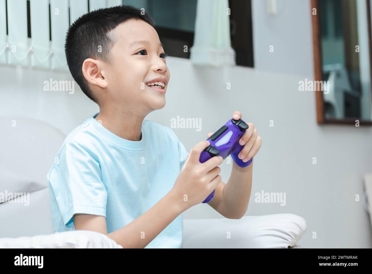 little Asian boy playing a video game. shot of a child holding a game ...