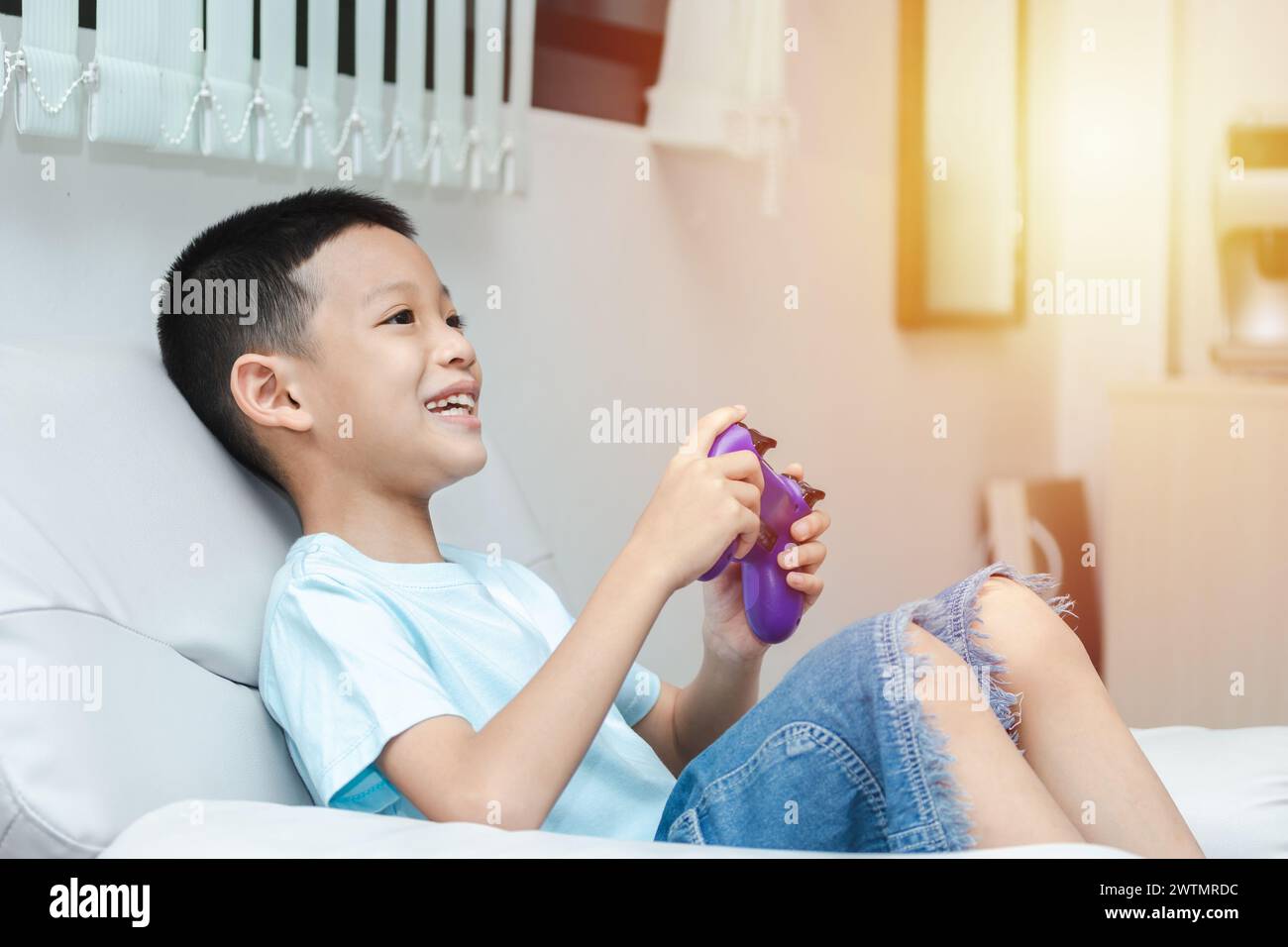 little Asian boy playing a video game. shot of a child holding a game ...