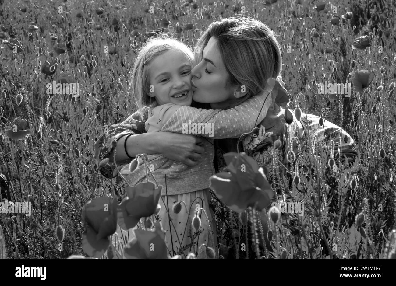 Mother and daughter hugging on flowering poppy field. Summer family ...