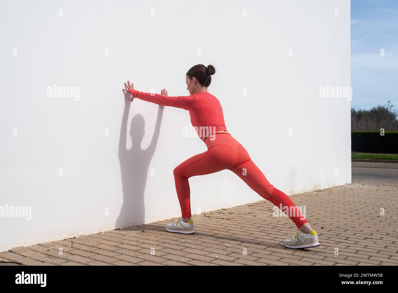 Sporty woman pushing against a white wall, warm up leg exercises Stock ...