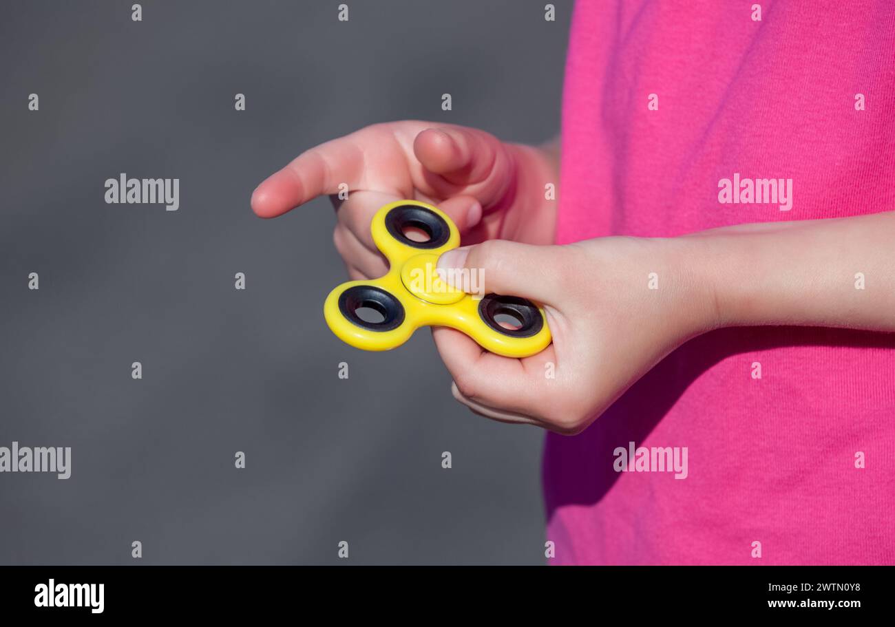 Little girl is playing a yellow spinner in her hand outdoors Stock ...