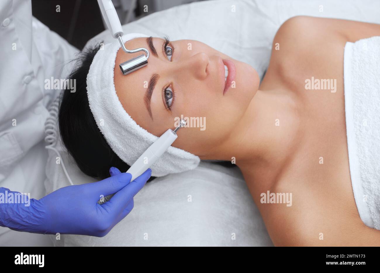 The cosmetologist makes the apparatus a procedure of Microcurrent therapy of a beautiful, young ...