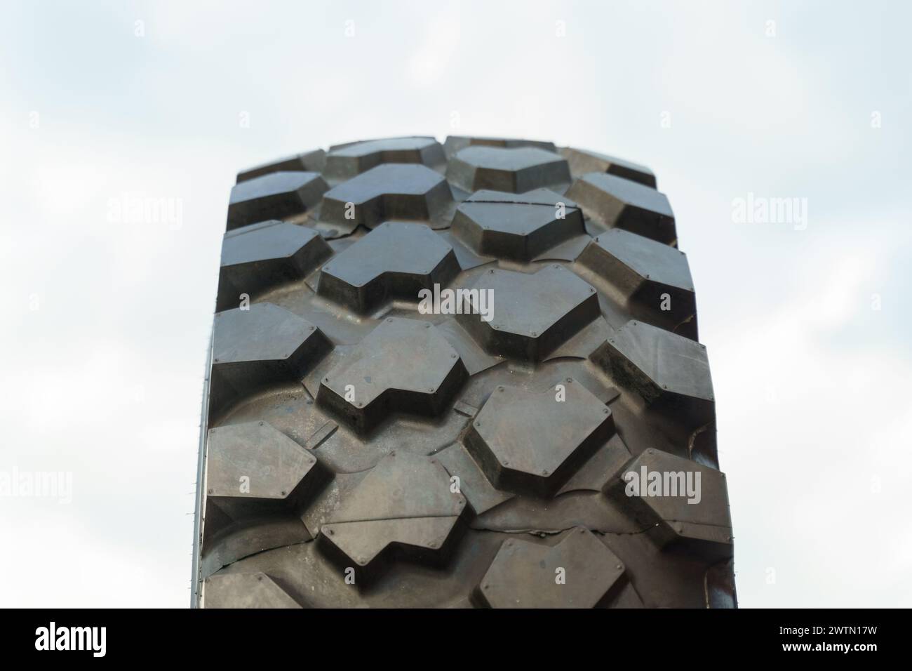 Detailed view of a tire with treads visible, set against a clear blue ...