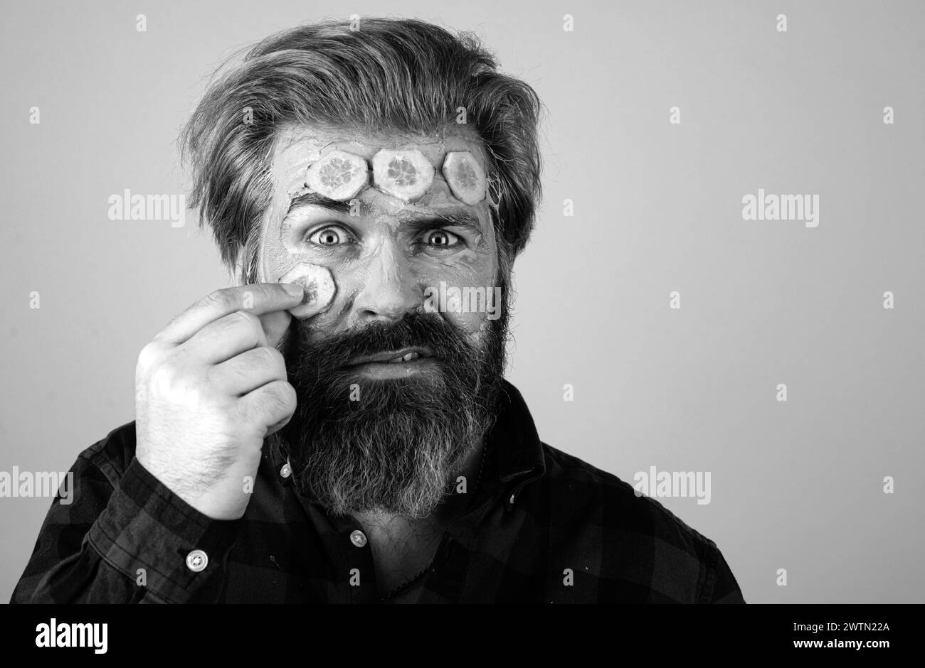 Funny male model with clay mask and cucumber slices on face. Spa ...