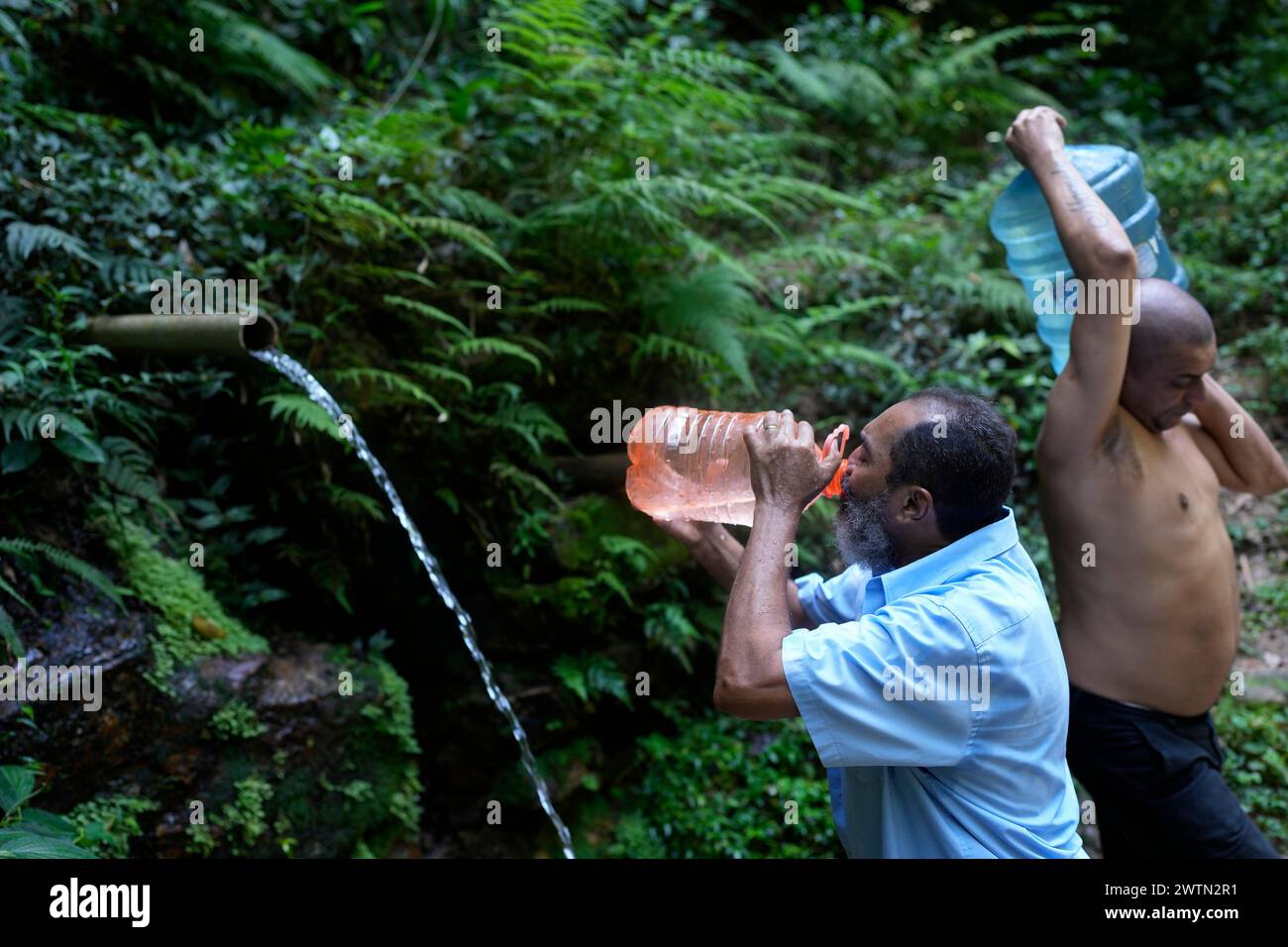 Residents drink and fill bottles with water that falls naturally down a ...