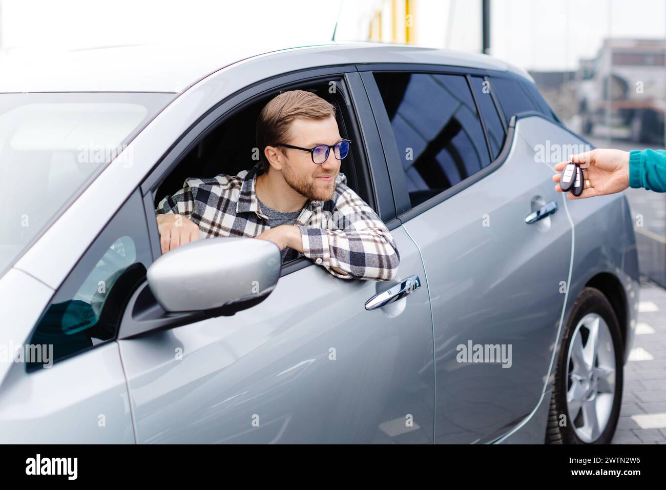Salesman giving key to customer in modern auto dealership. Concept of ...