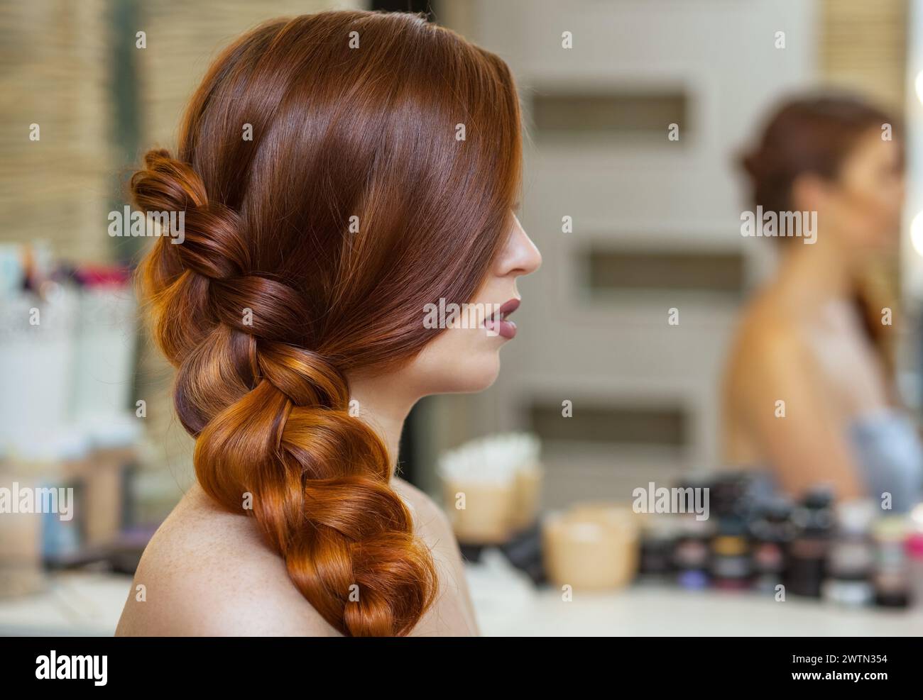 Beautiful girl, with long, red-haired hairy. hairdresser weaves a ...