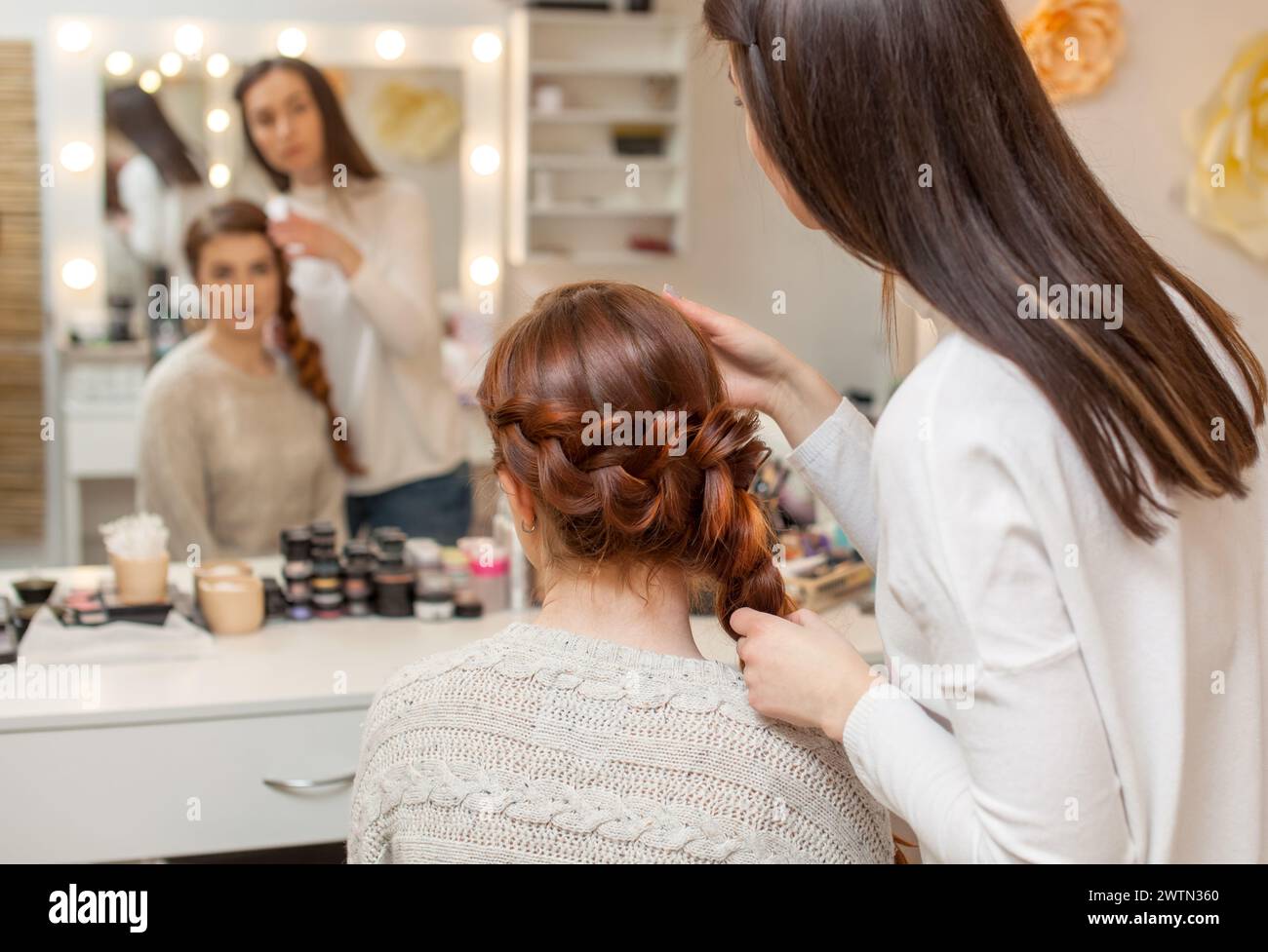 Beautiful girl, with long, red-haired hairy. hairdresser weaves a ...
