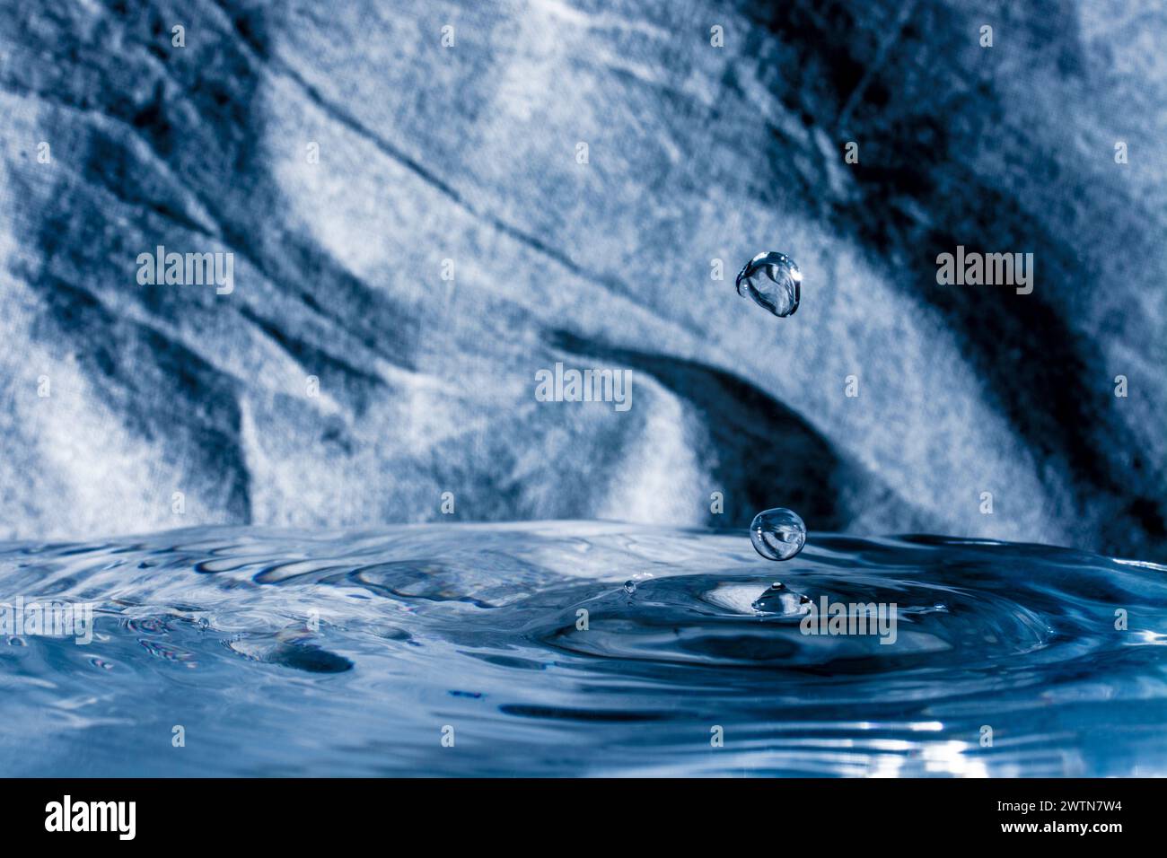 Photograph of water droplet hitting water surface and bouncing back up ...