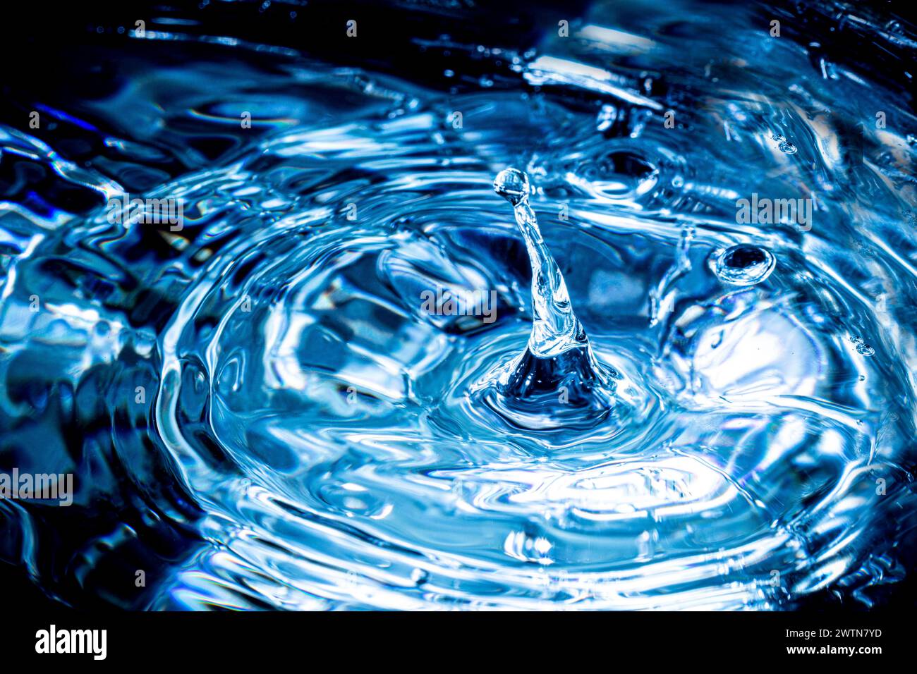 Photograph of water droplet hitting water surface and bouncing back up ...