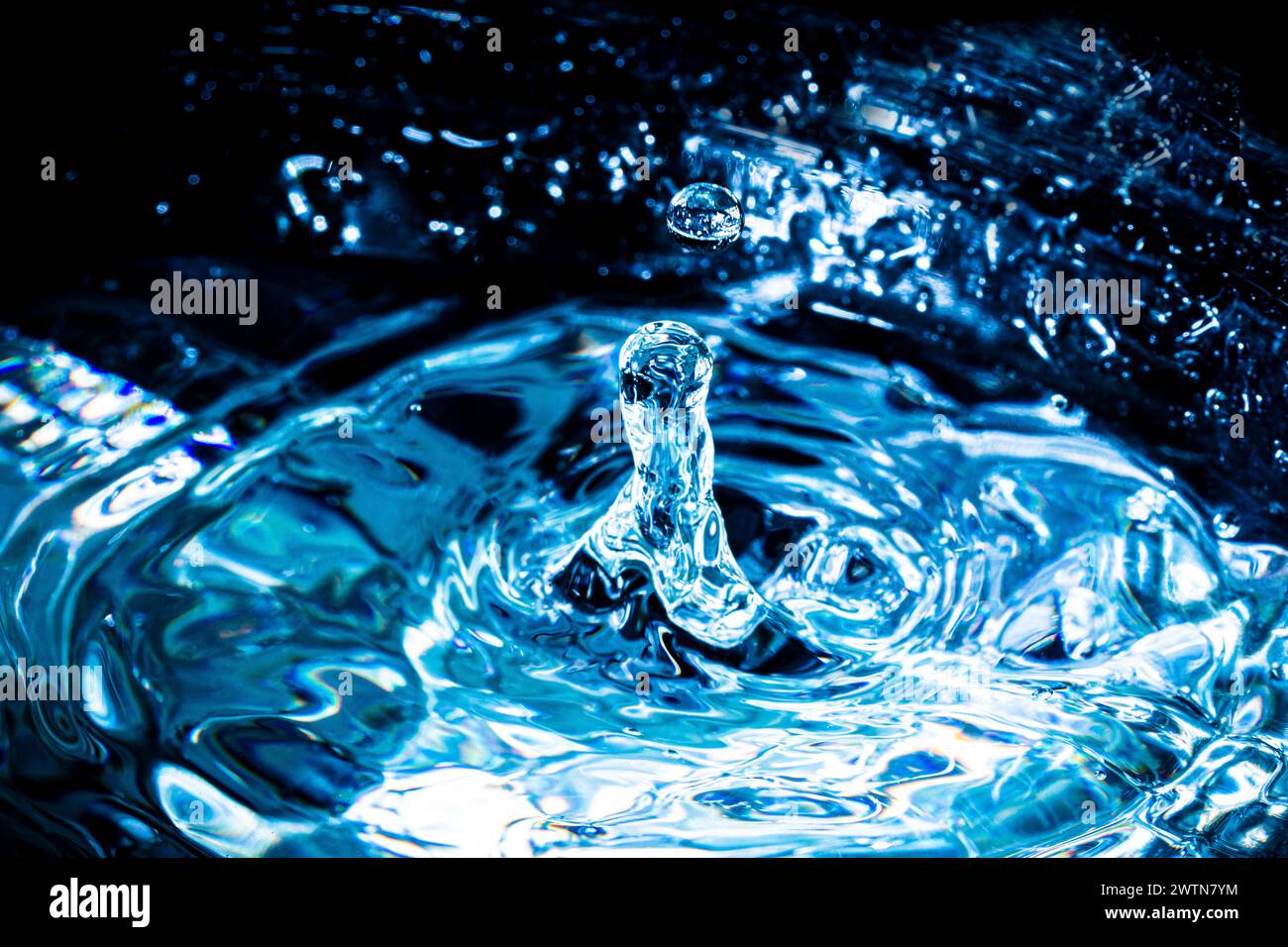 Photograph of water droplet hitting water surface and bouncing back up ...