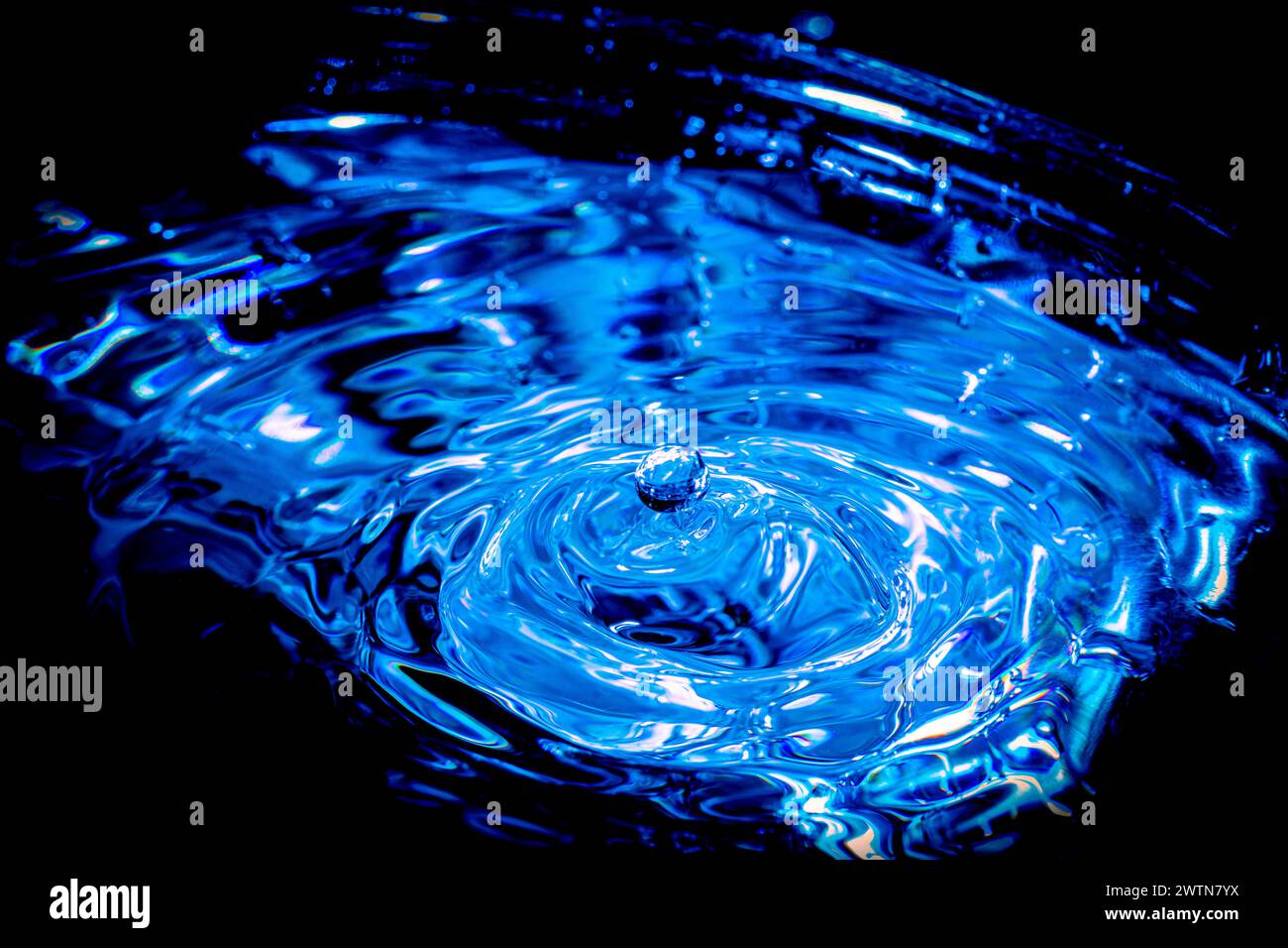 Photograph of water droplet hitting water surface and bouncing back up ...