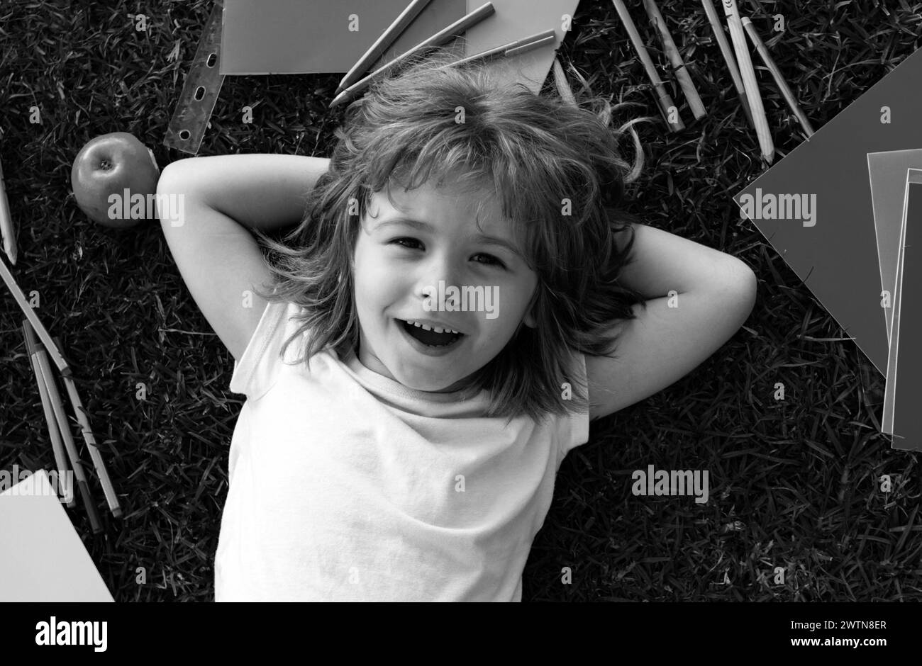 Fanny smiling face of cute smart school boy, lie on grass. Happy pupil Stock Photo - Alamy