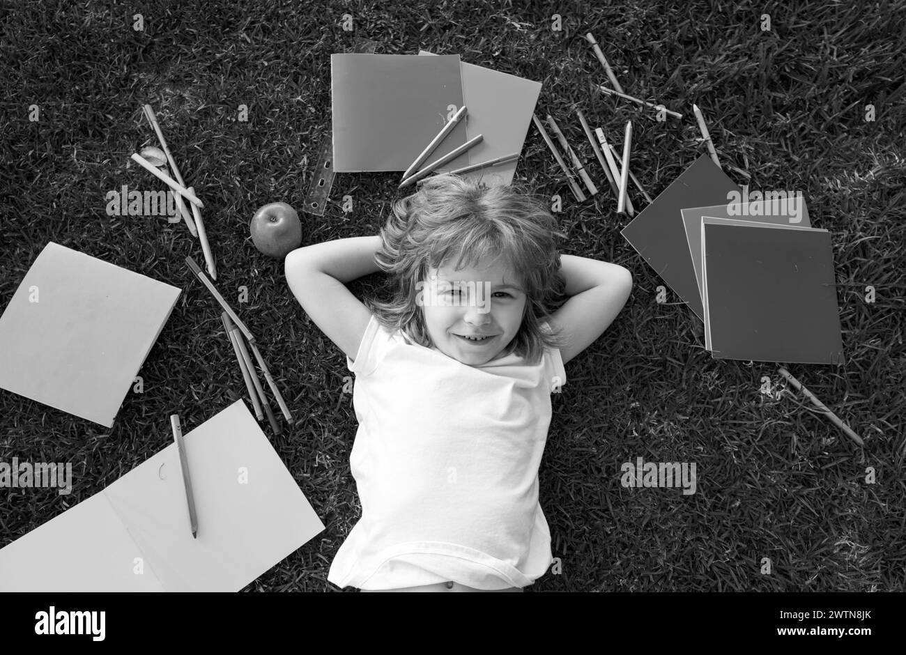 Portrait of cute smart clever school boy nerd doing homework, lie on ...