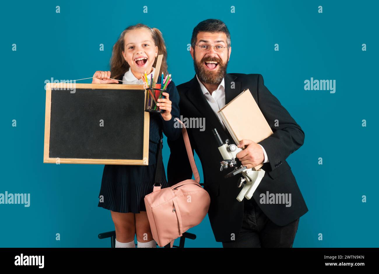 Funny little schoolgirl in school uniform having fun in studio ...