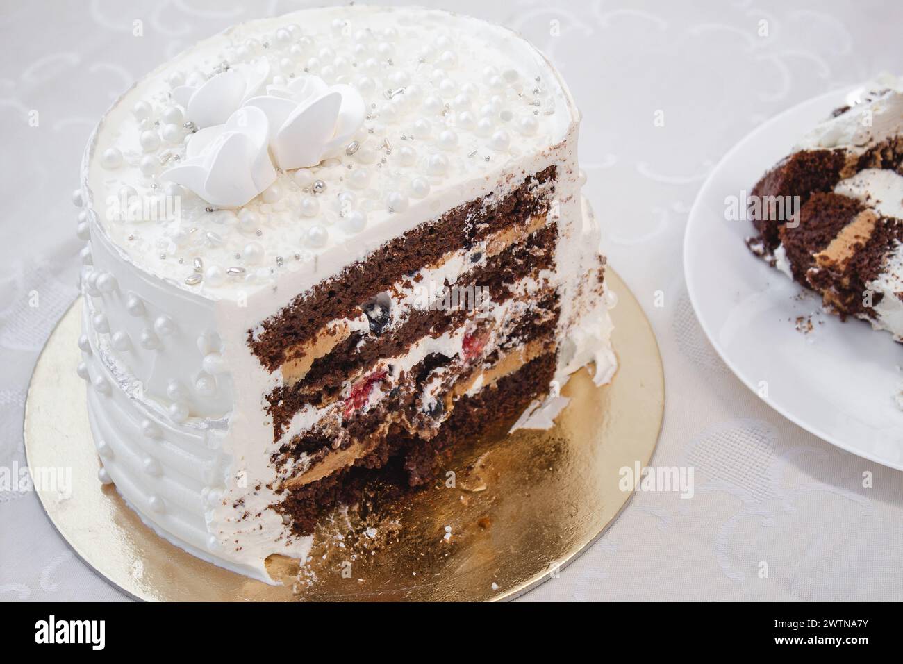 White party cake with pearls and white icing and red fruit and ...