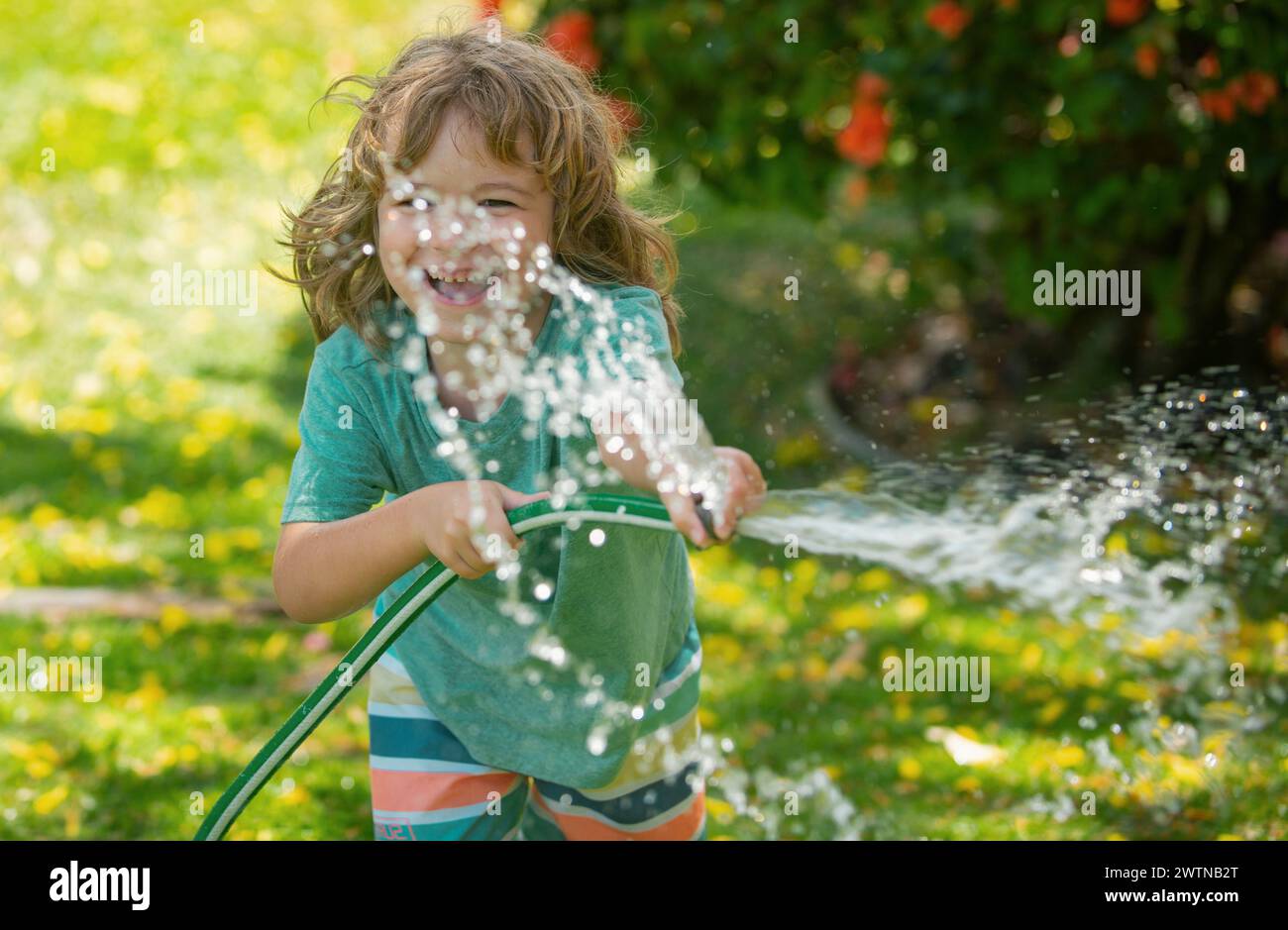 Funny kid playing with garden hose in backyard. Child having fun with ...
