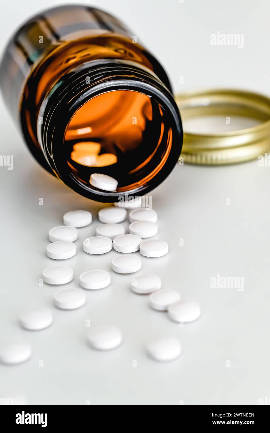 White Tablets Scattered on Table Next to Brown Glass Vial, on White ...