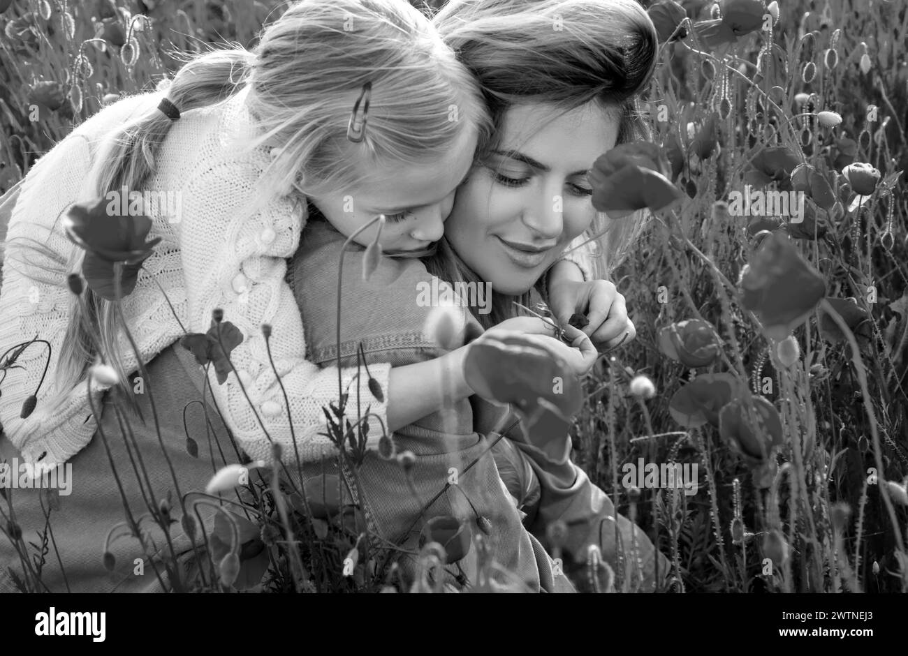 Mother and daughter hugging in a poppies meadow. Mom and child girl ...