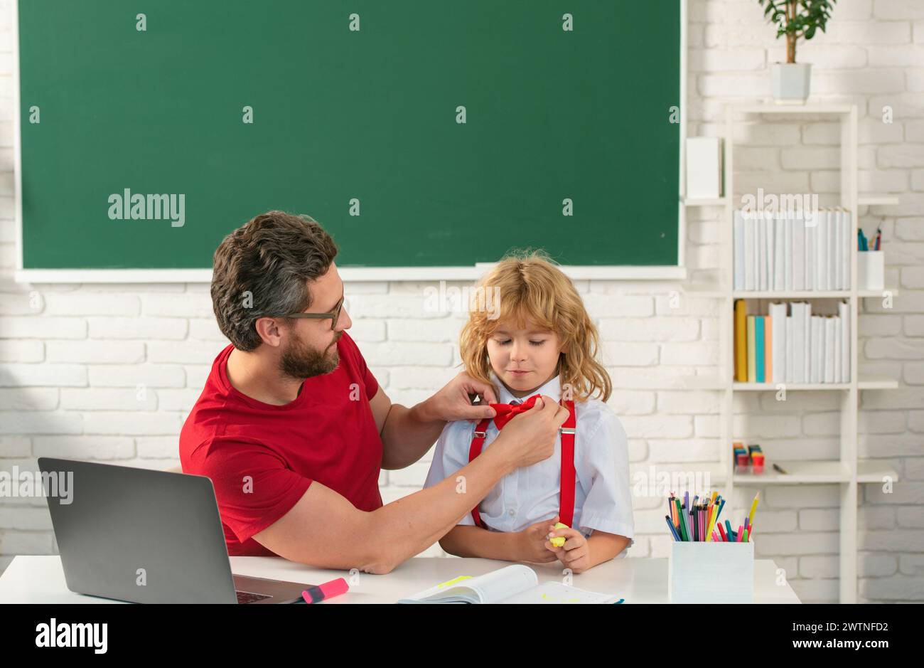 Elementary school boy in classroom on lesson. Teacher explaining to ...