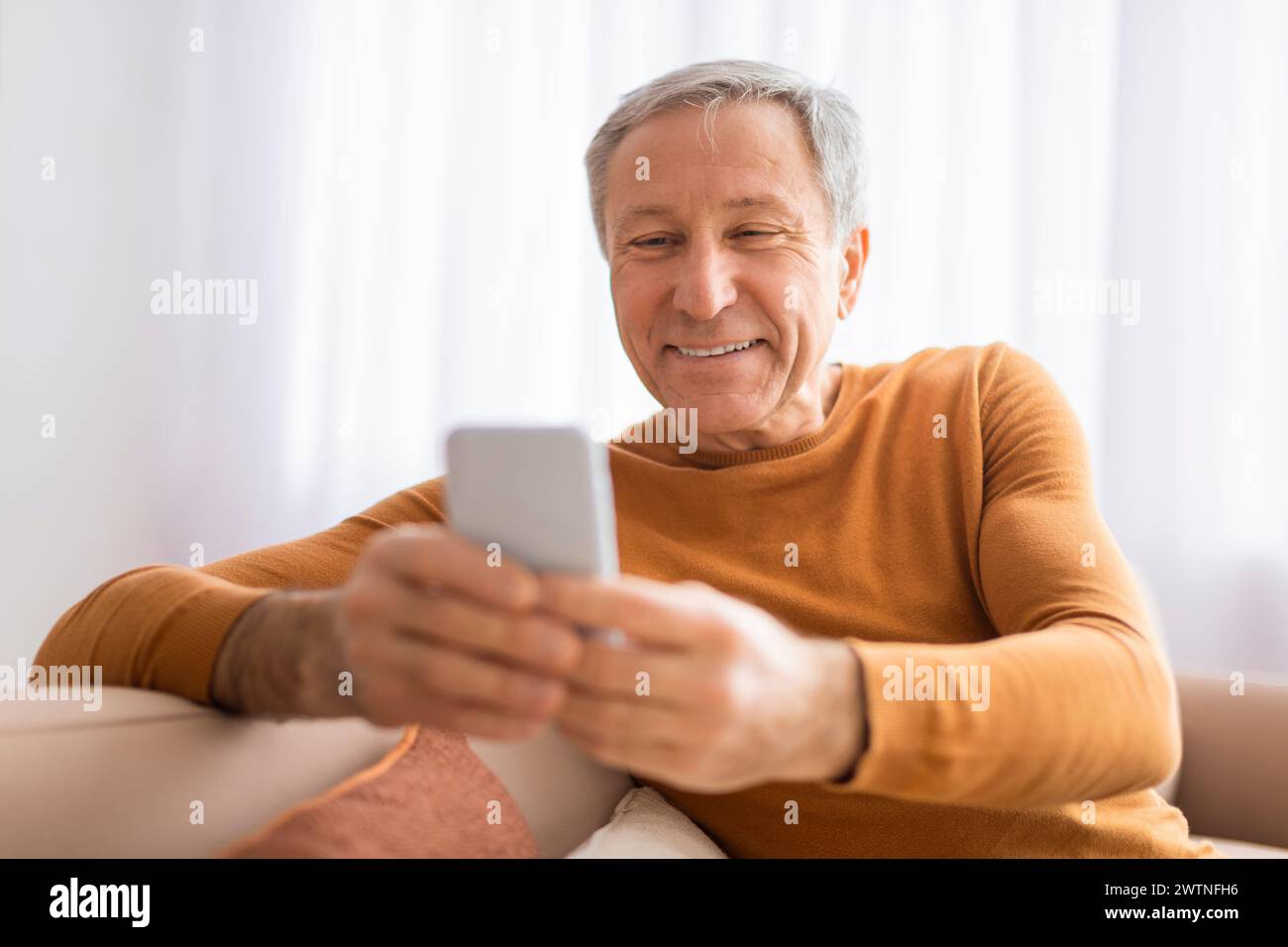 Older man viewing smartphone with pleasant smile Stock Photo - Alamy