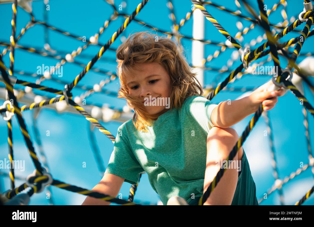 Portrait of cute boy child doing rock climbing in the playbackground ...