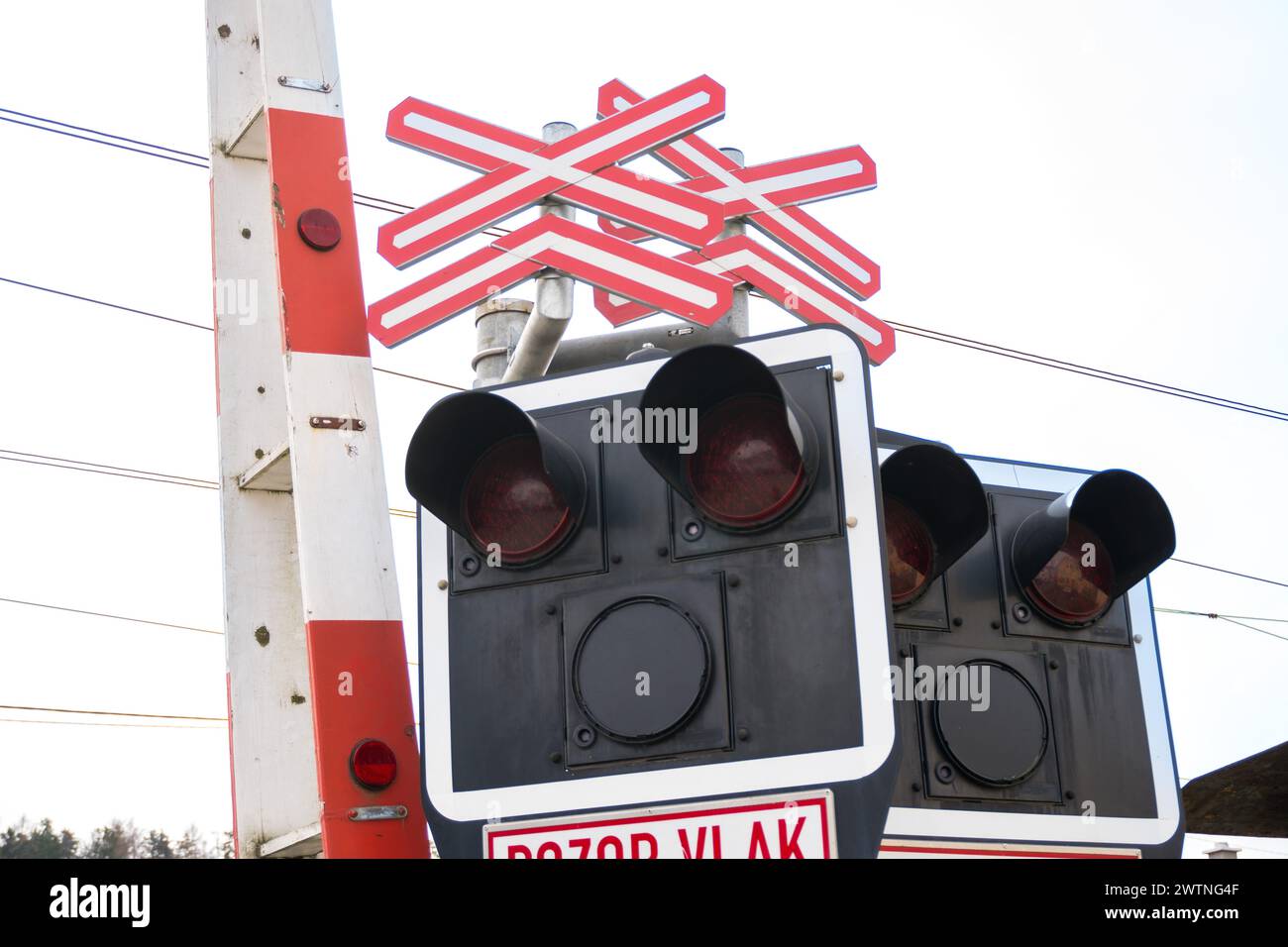 Railway crossing sign and red traffic light over a level crossing ...
