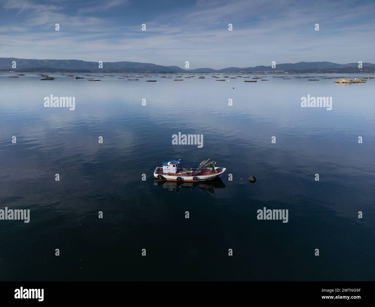 A small wooden fishing boat anchored in the Arousa estuary. Mussel ...