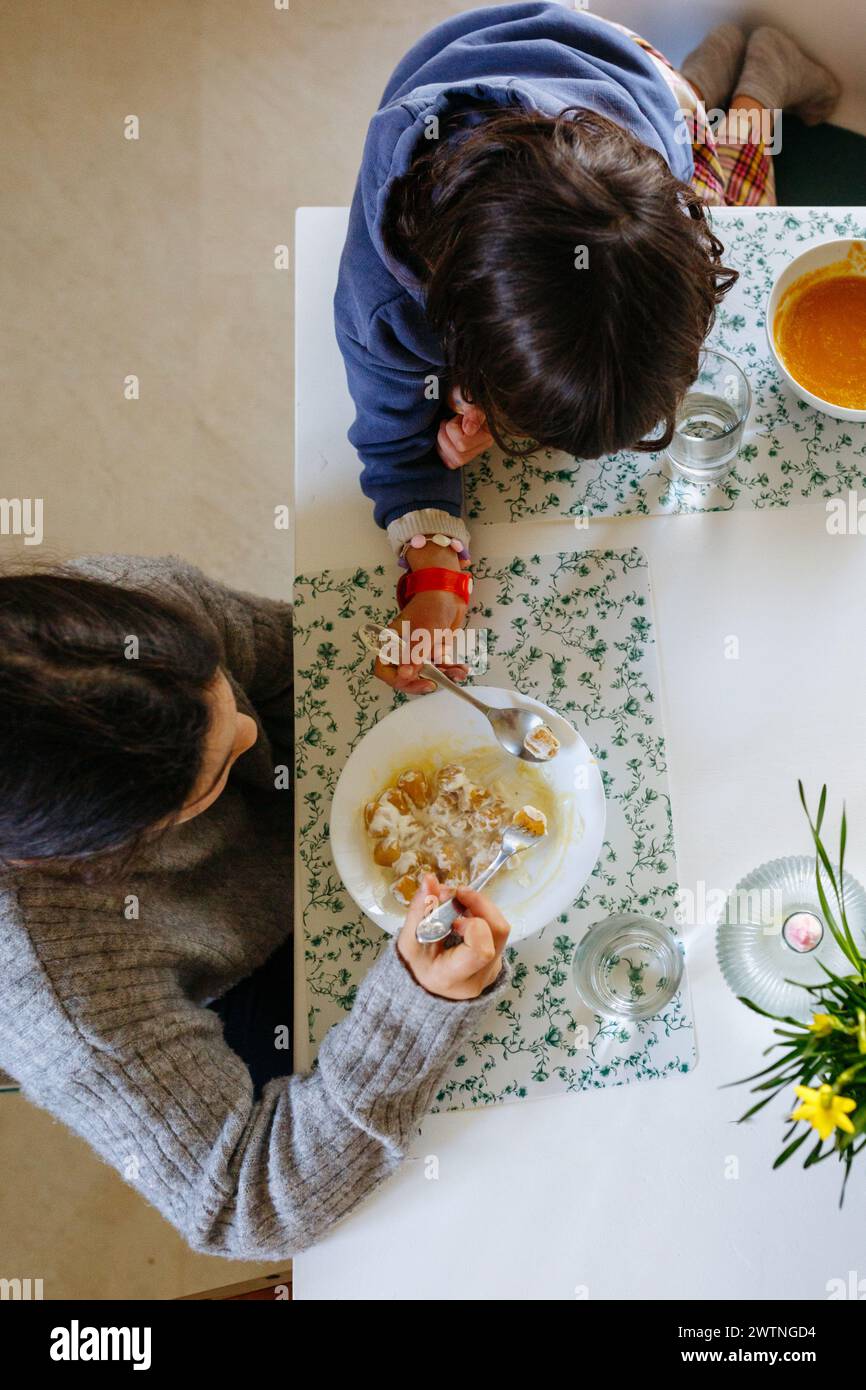 upper view of one child trying food from the plate of another child at ...