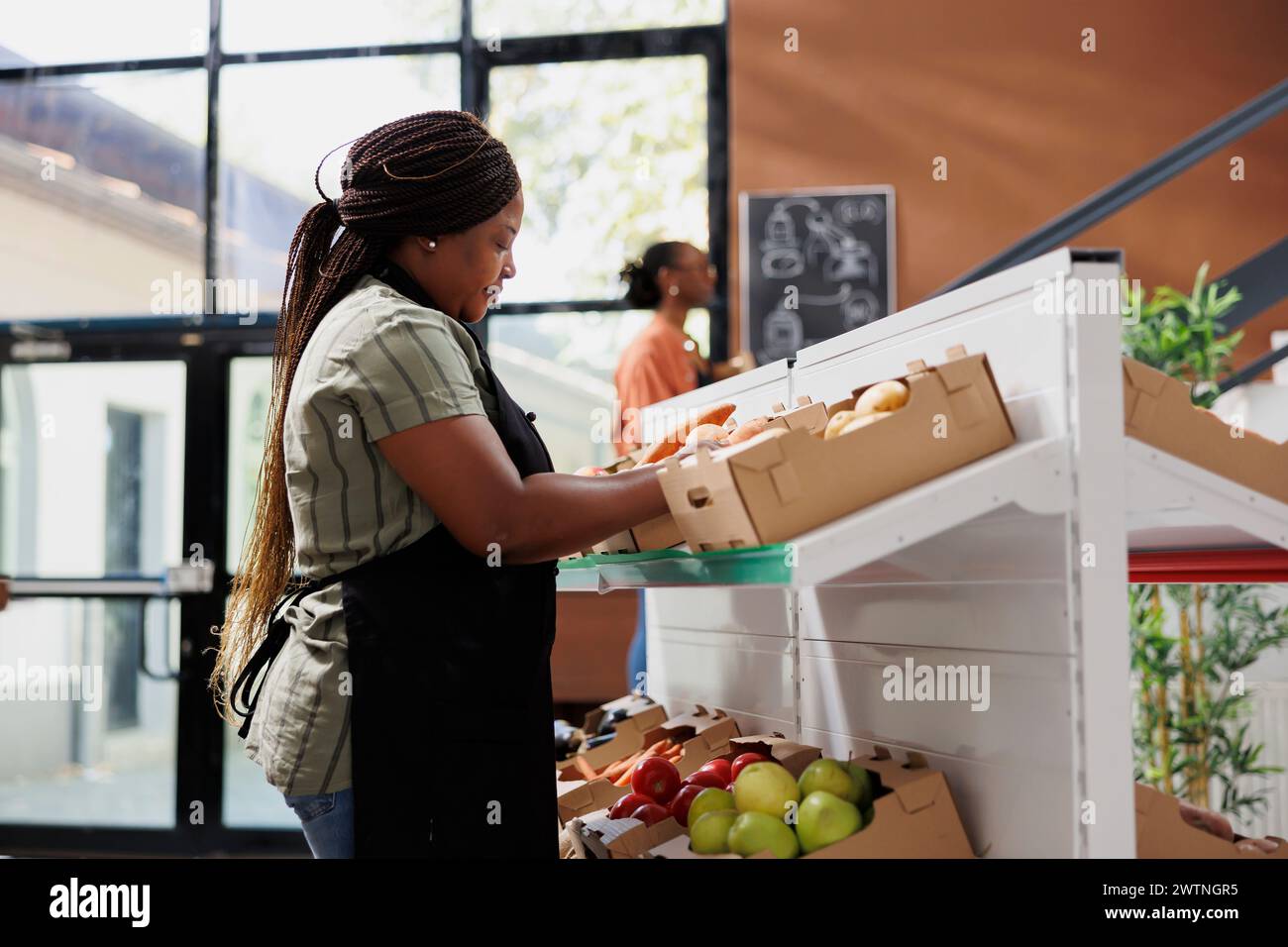 African american vendor working in eco friendly grocery shop, arranging ...