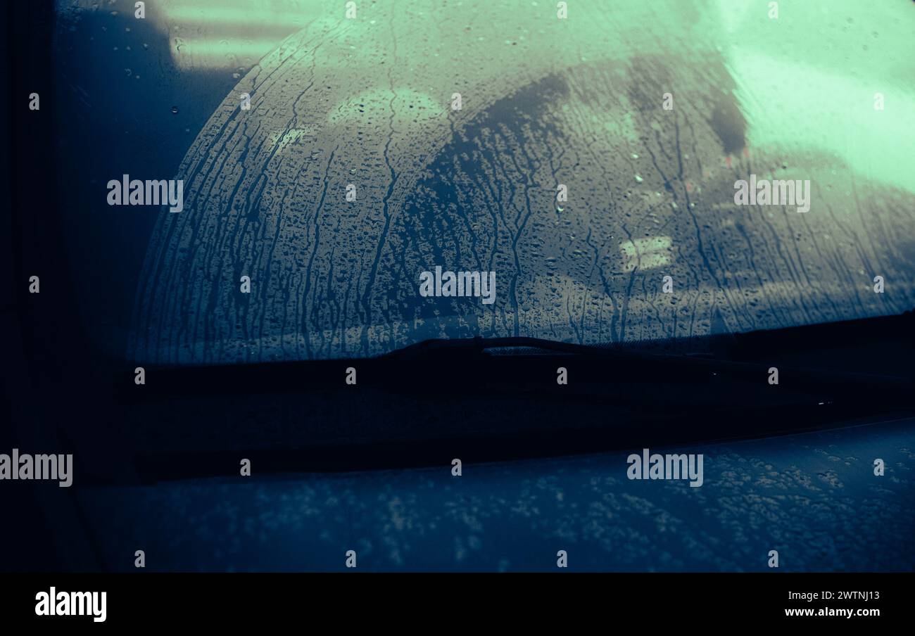 The windshield of the car was covered with drops of heavy rain, as the ...