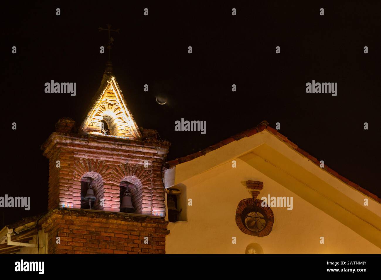 Bell tower of San Antonio church illuminated with warm light at night ...